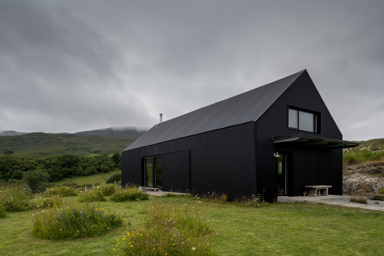 Une maison en aluminium noir et son studio près d'un loch