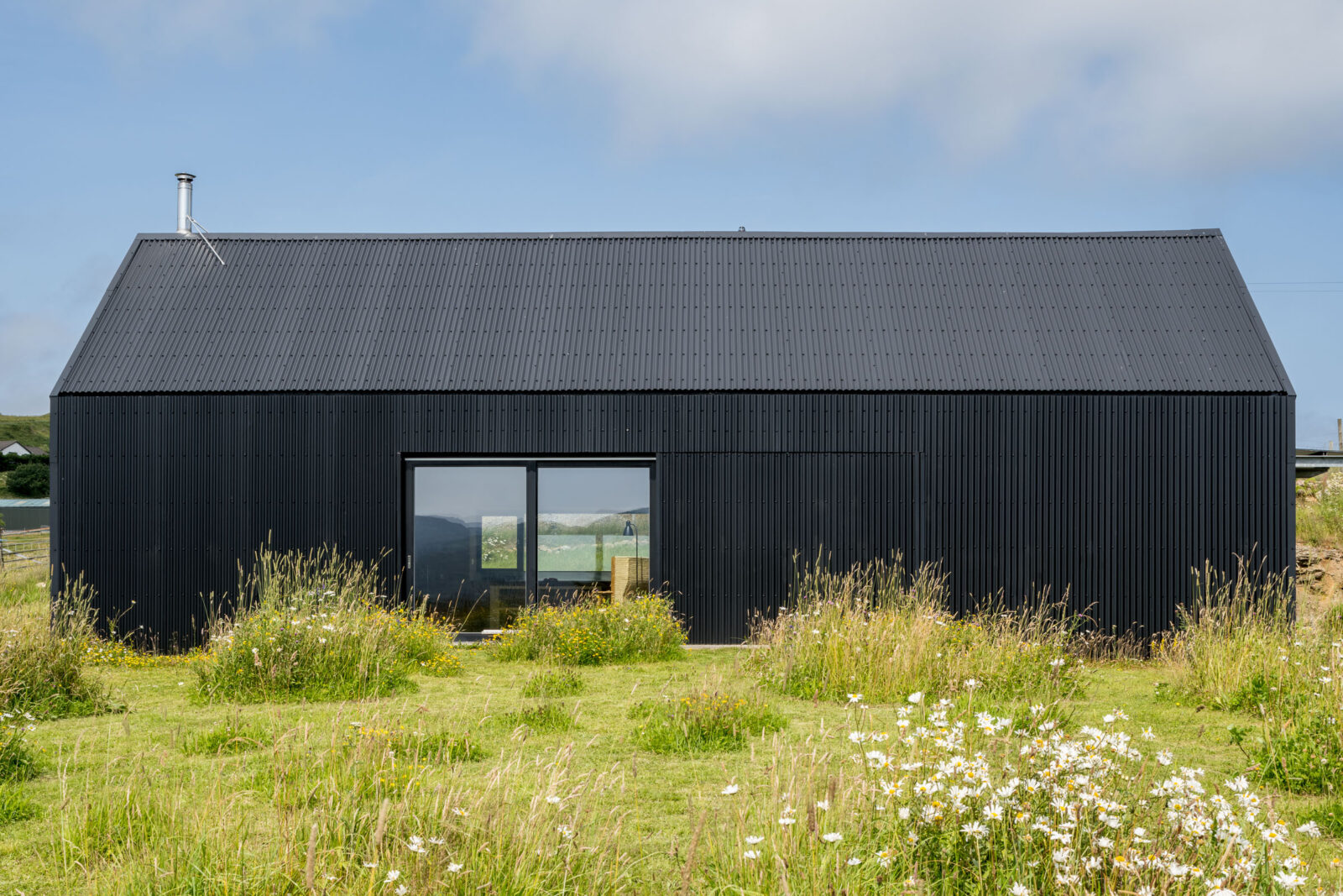 Une maison en aluminium noir et son studio près d'un loch