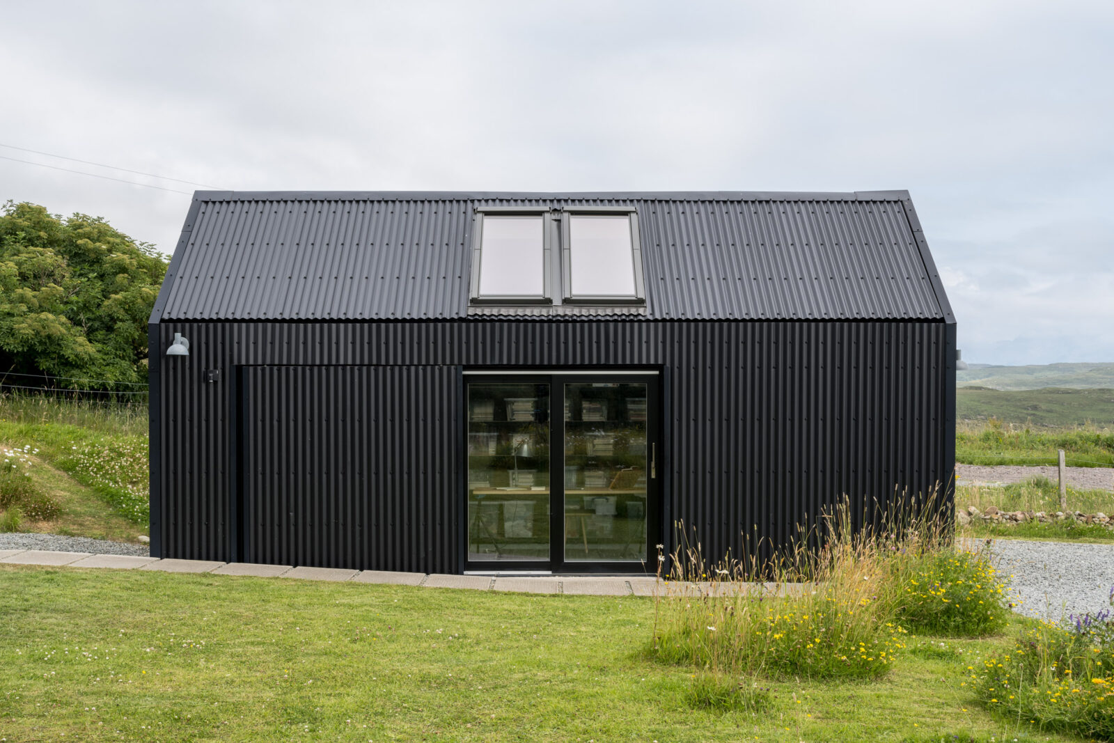Une maison en aluminium noir et son studio près d'un loch
