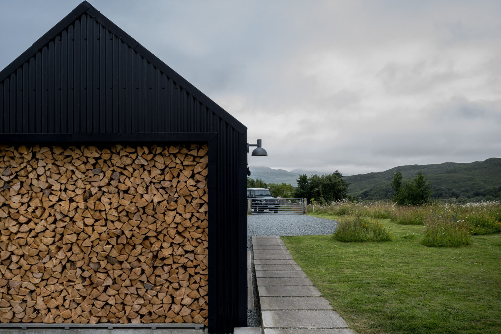 Une maison en aluminium noir et son studio près d'un loch