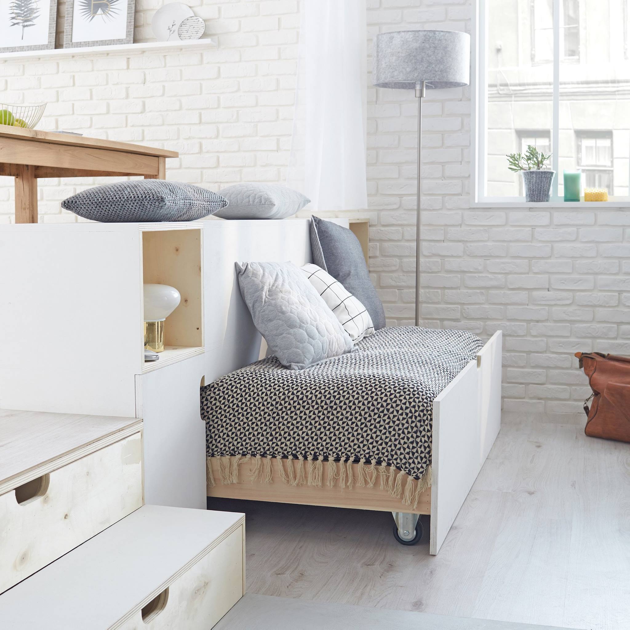 Un lit caché sous une estrade dans le salon d'un studio