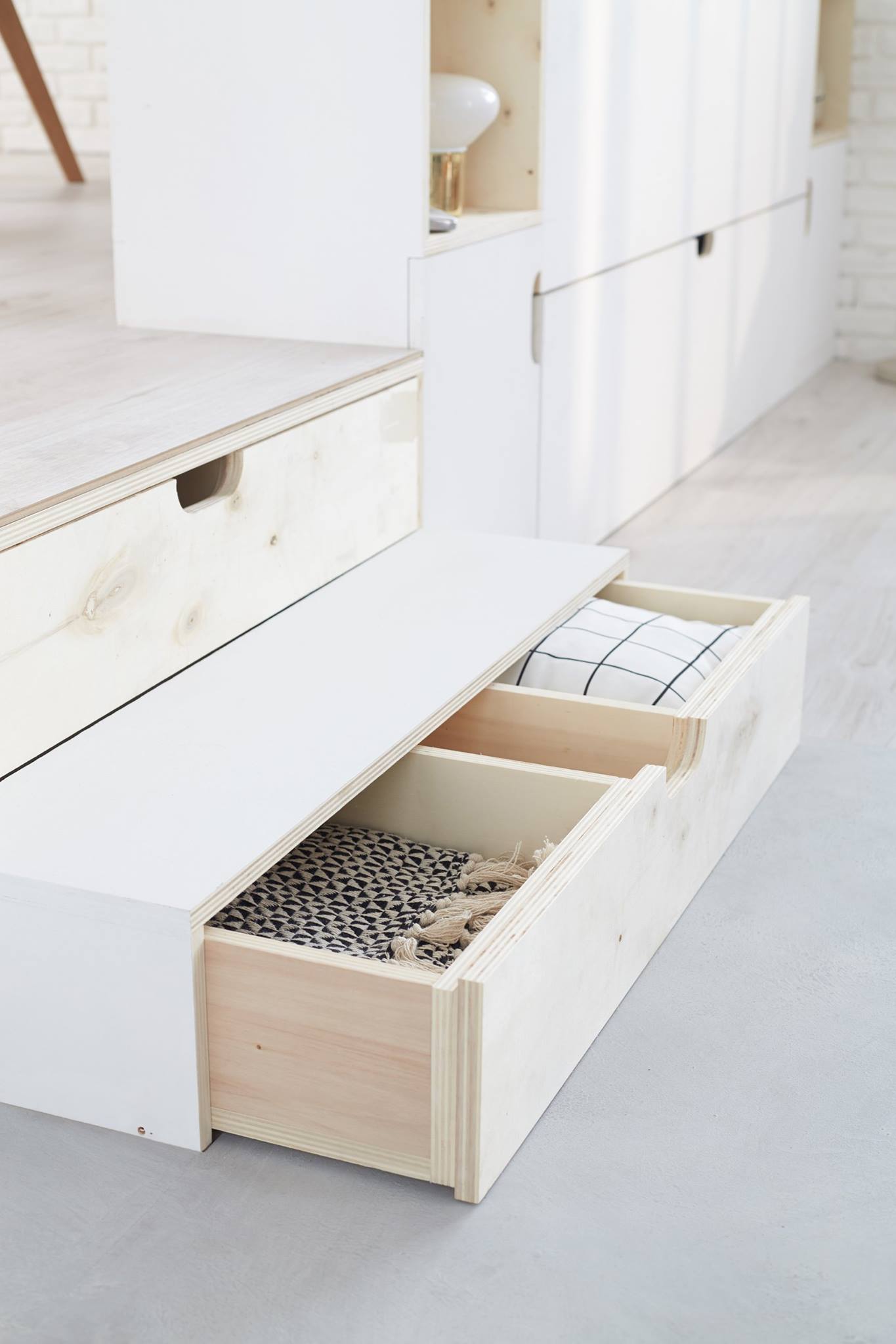 Un lit caché sous une estrade dans le salon d'un studio